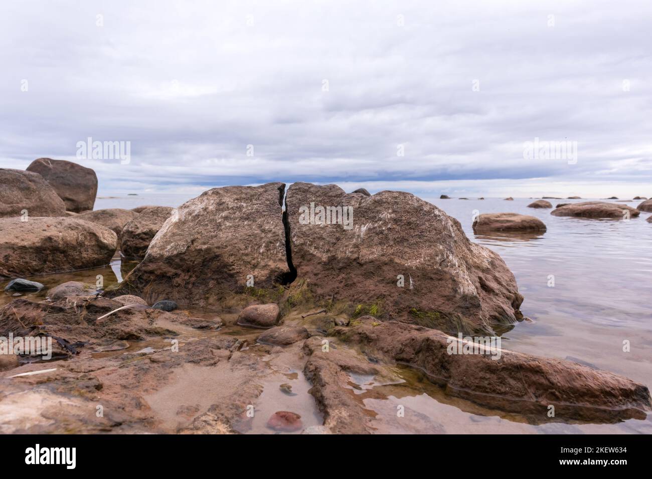 A large stone split in half in the sea sand next to the sea Stock Photo ...