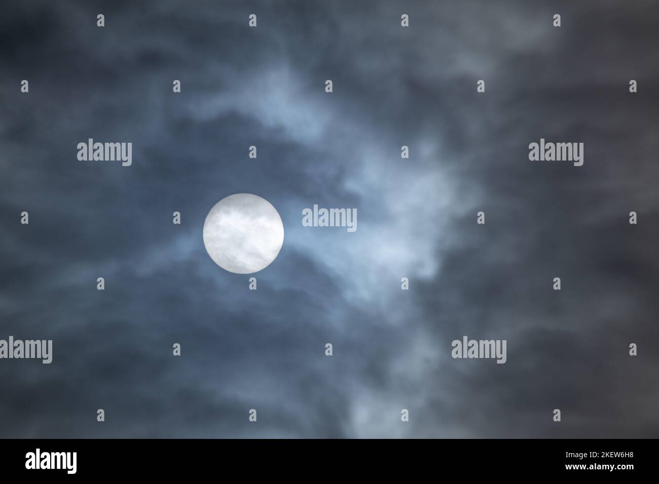 Big bright sun circle looking through clouds in daytime. Sun in dark ...