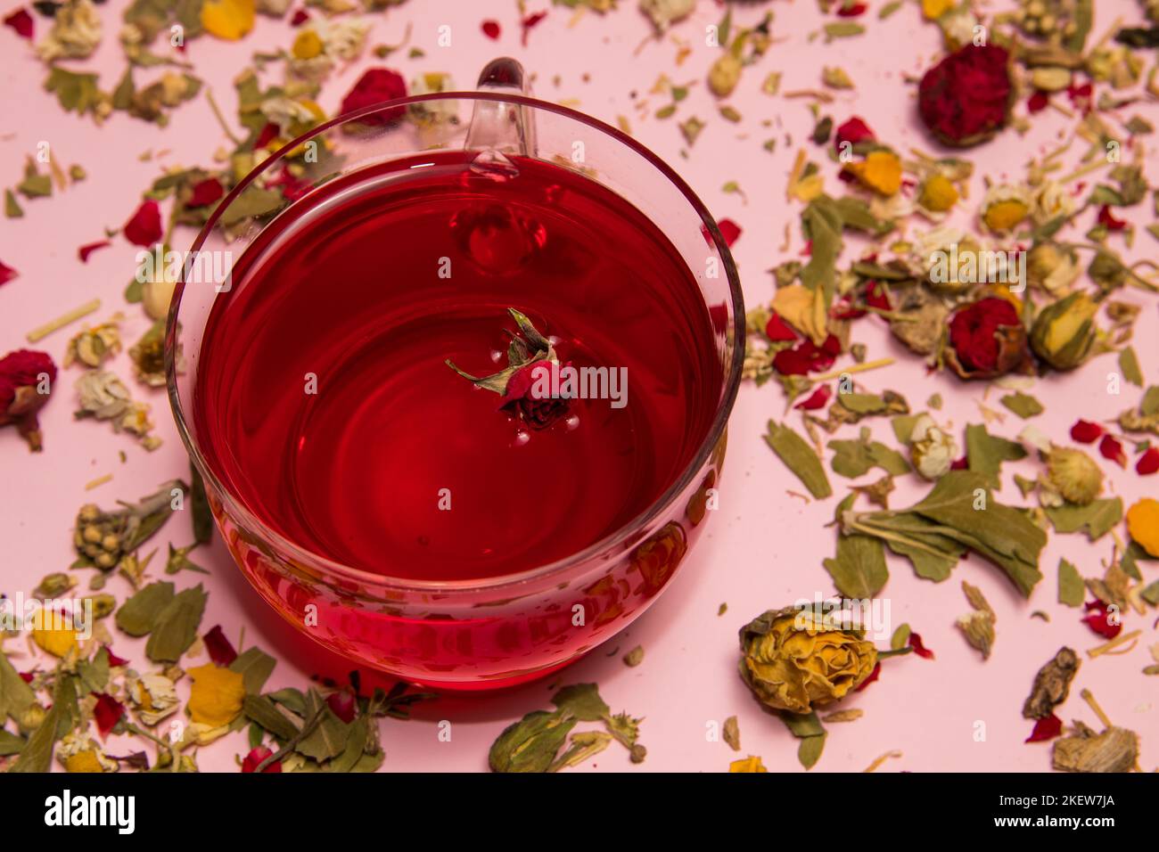 Tea in a glass cup with a rosebud on a background with herbal and ...