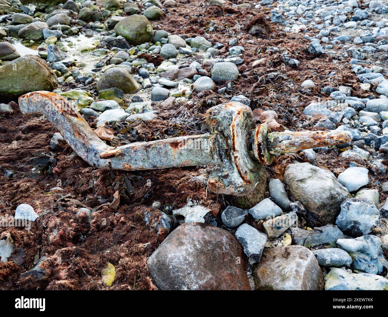 Old rusty anchor forgotten on stony coast. Rusty steel damaged by ...