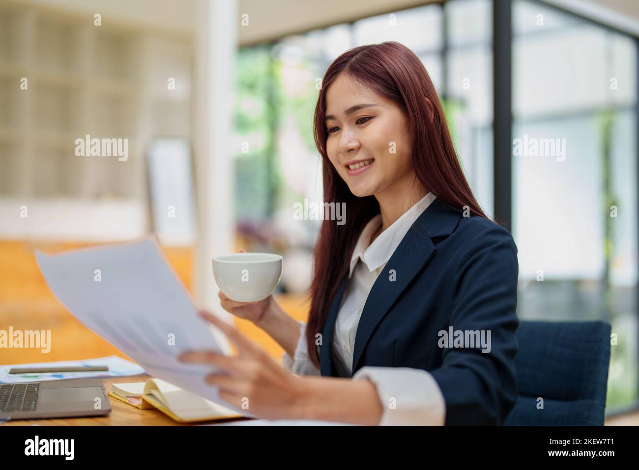 Asian female worker using computer and budget documents on desk Stock ...