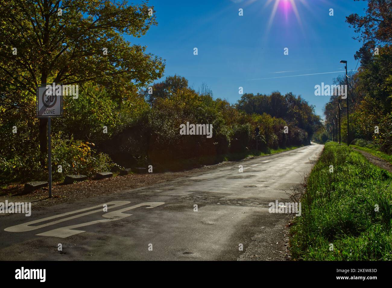 straight empty suburban road at the end of a 30 km/h-zone in bright ...