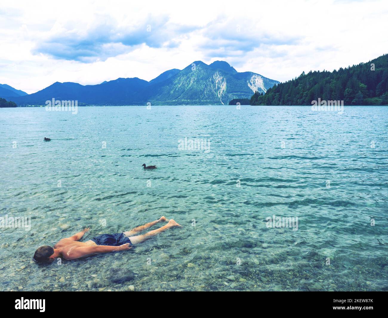 Athletic teenager boy shows how a drowned body floats in low water ...