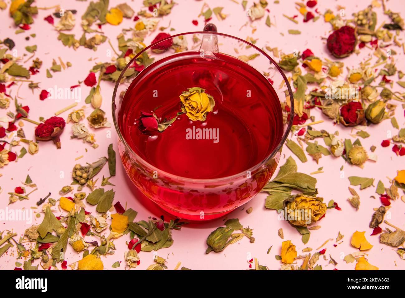 Tea in a glass cup with a rosebud on a background with herbal and ...