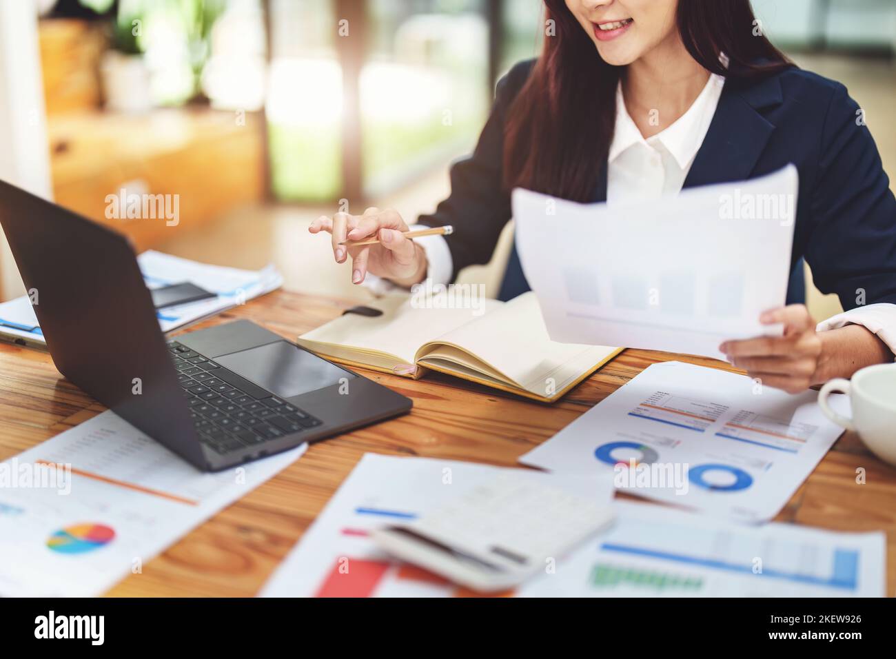 Asian female worker using computer and budget documents on desk Stock ...