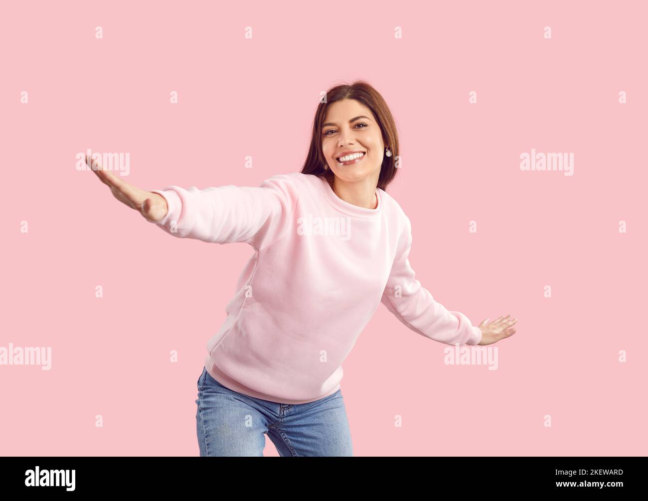 Happy fashion model in pink sweatshirt smiling and posing on pink ...