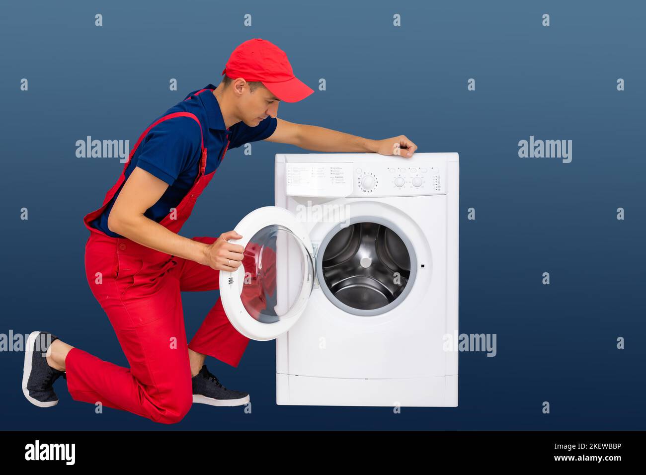 Repairman is repairing a washing machine on the blue background Stock ...