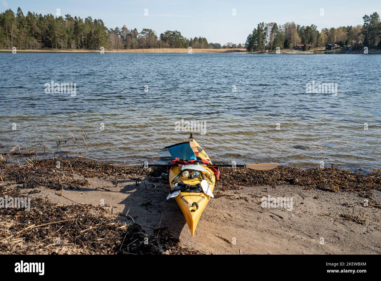Yellow sea kayak pulled up onto the shore of an island in the Stockholm ...
