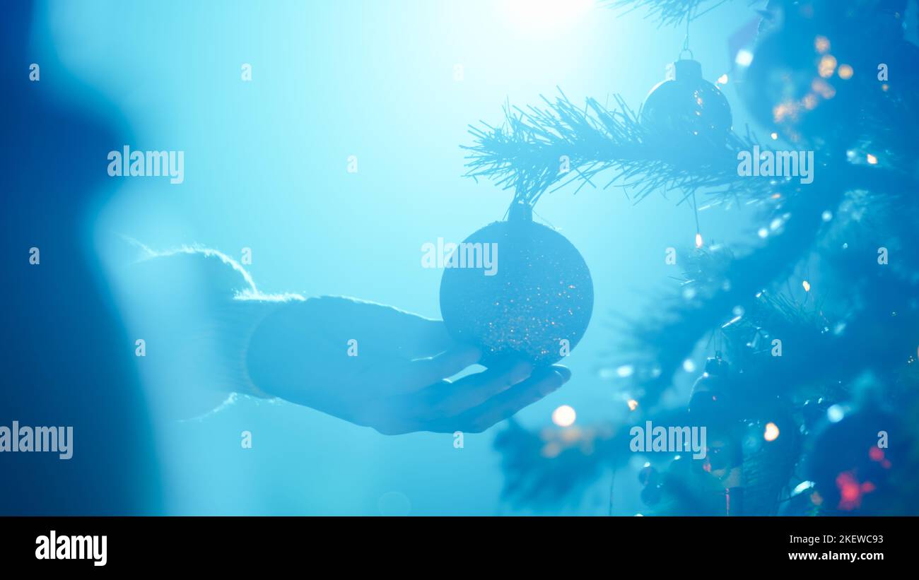 Hand Hangs Christmas Ball On Tree at moon light Stock Photo - Alamy