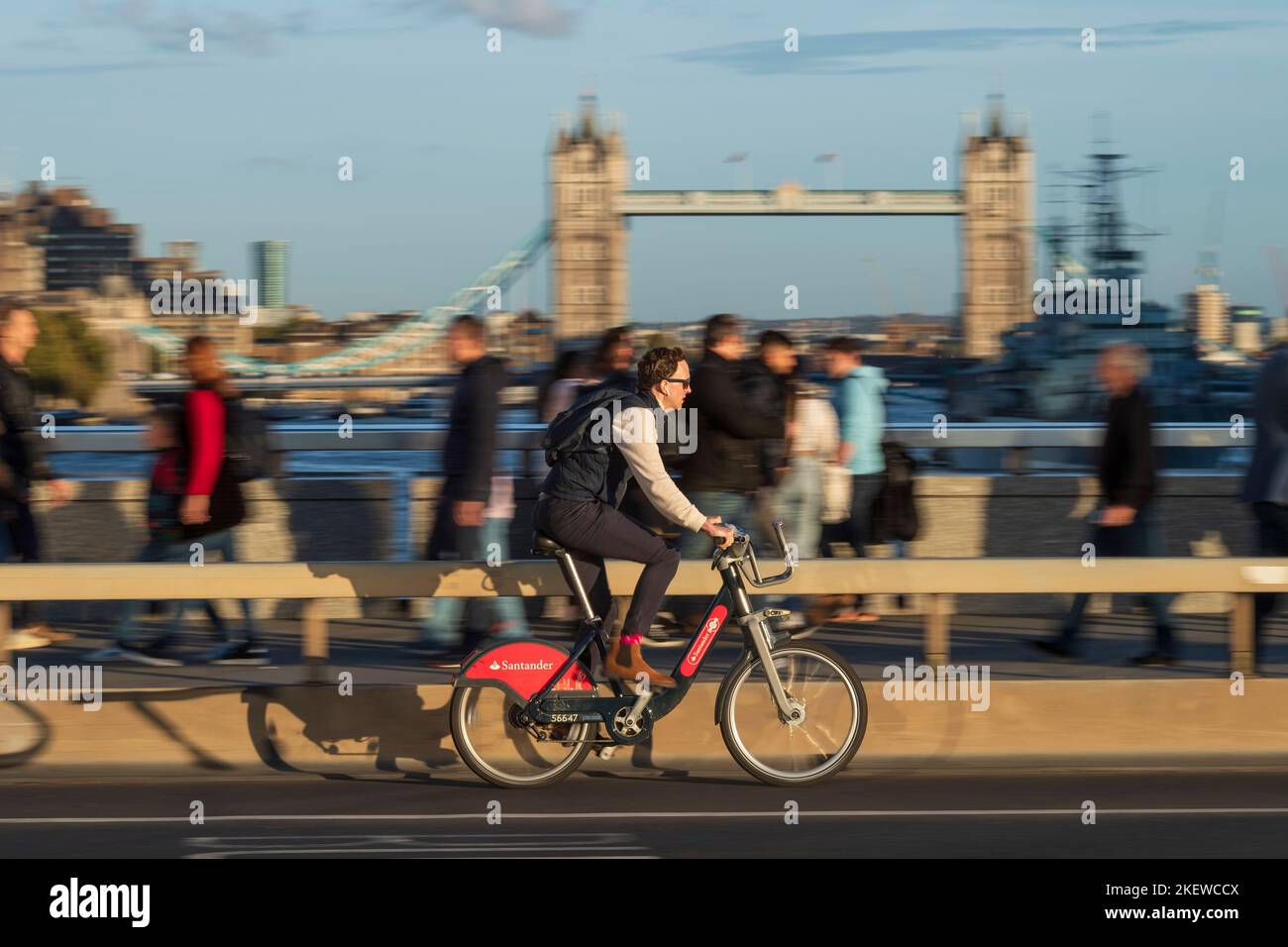 A man cycling across London Bridge during rush hour, on a Transport for London Santander Cycles ...