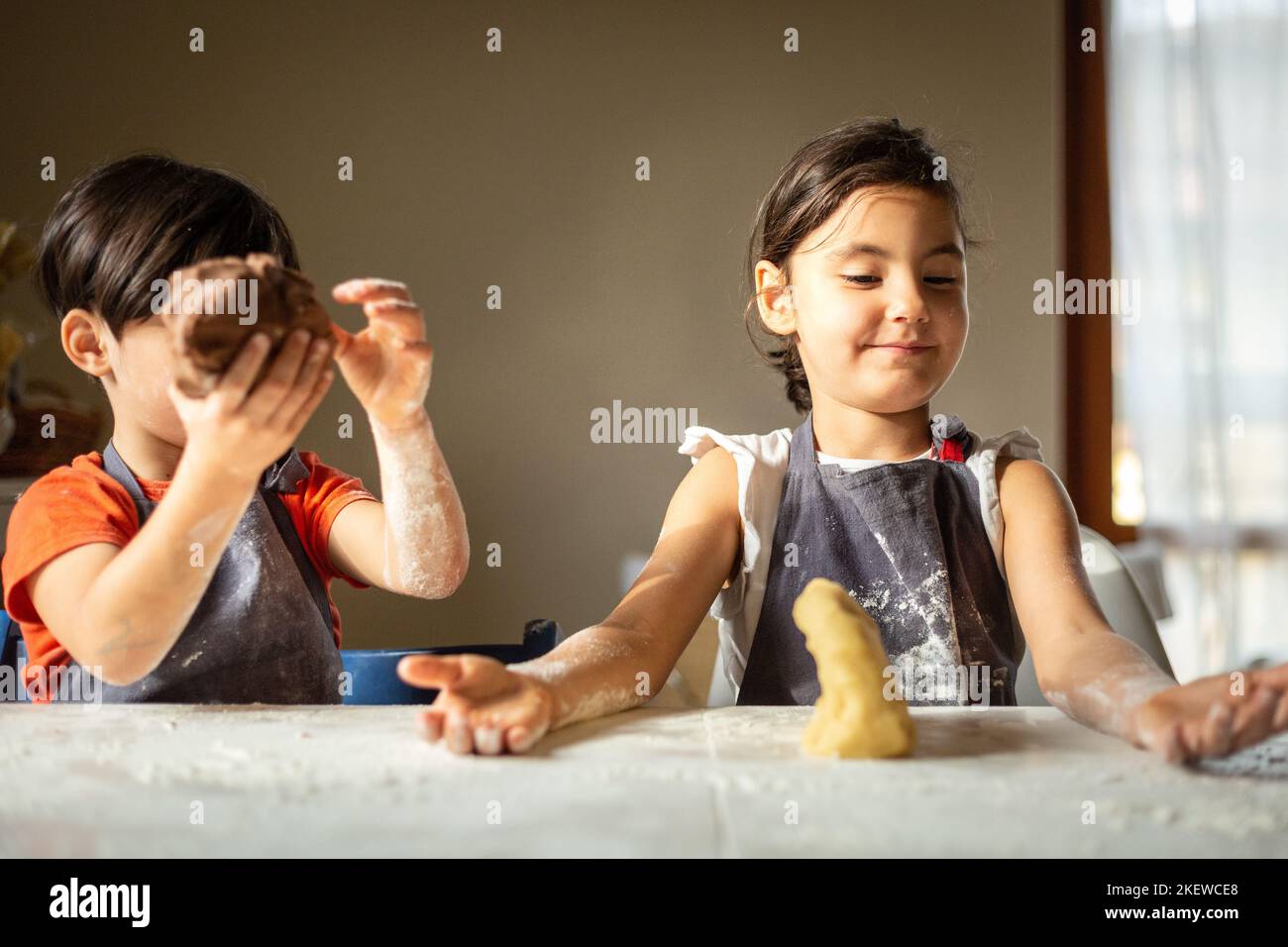 two happy girls making a cake athome Stock Photo - Alamy