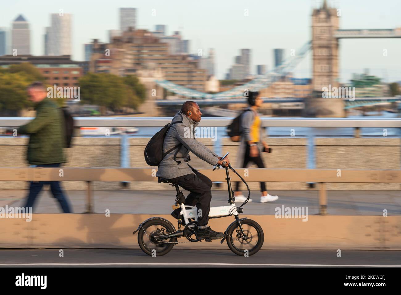 A man cycling an e-bike, during rush hour, across London Bridge, London, UK. 18 Oct 2022 Stock ...