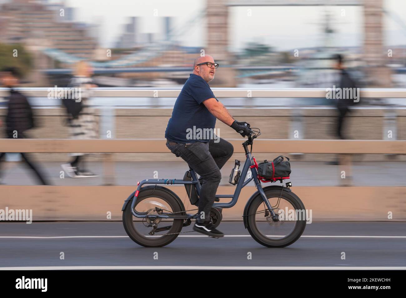 A man cycling on an e-bike during rush hour, across London Bridge ...