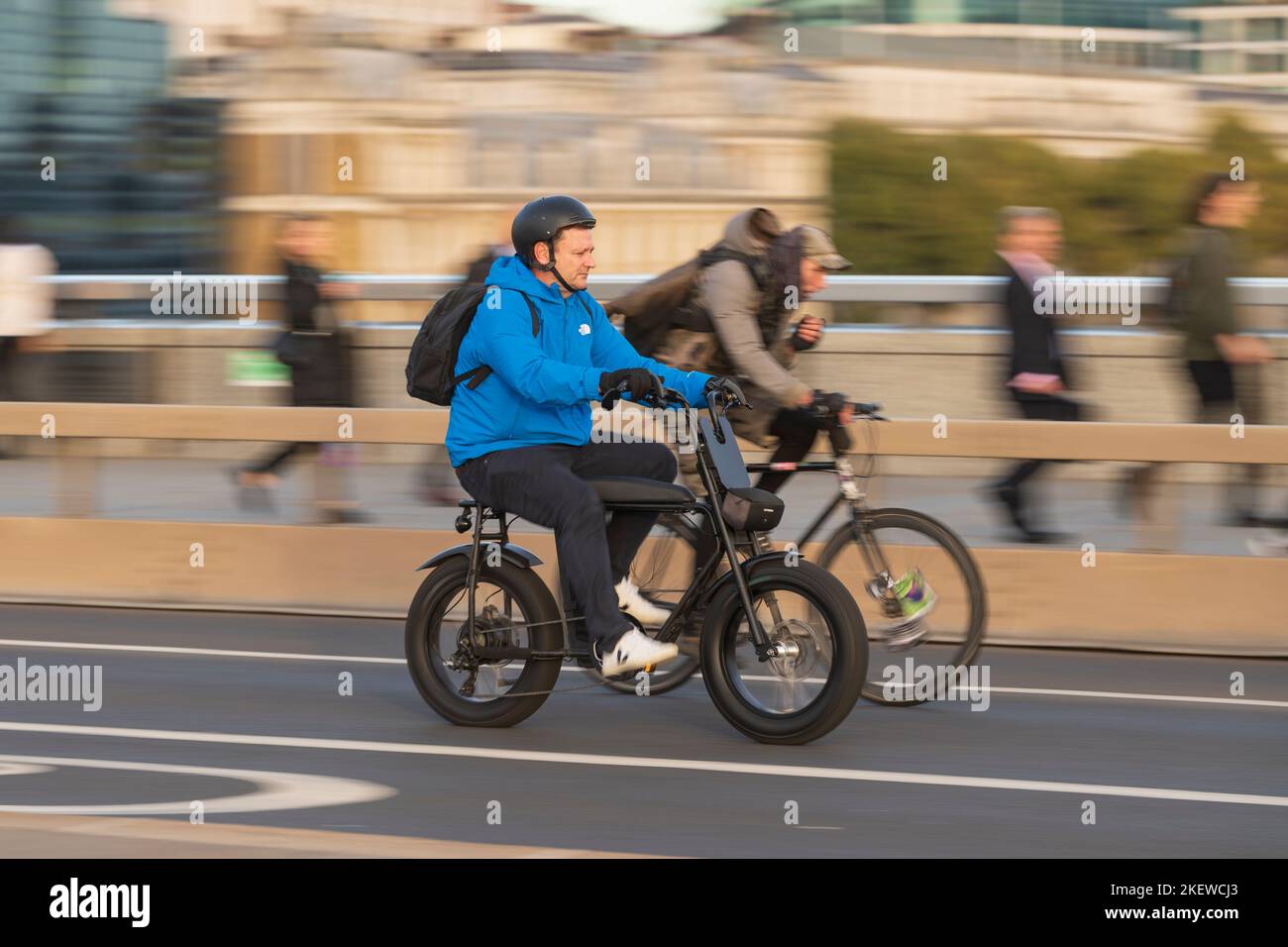 A man cycling on an e-bike during rush hour, across London Bridge, London, UK. 18 Oct 2022 Stock ...