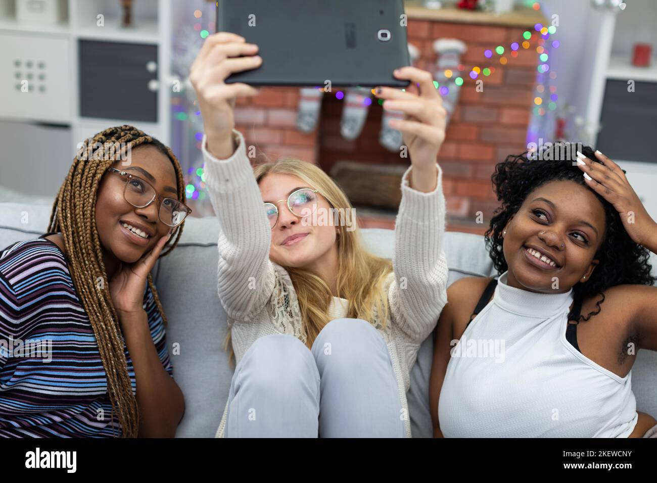 Girls take a selfie with a tablet next to a fireplace decorated for ...