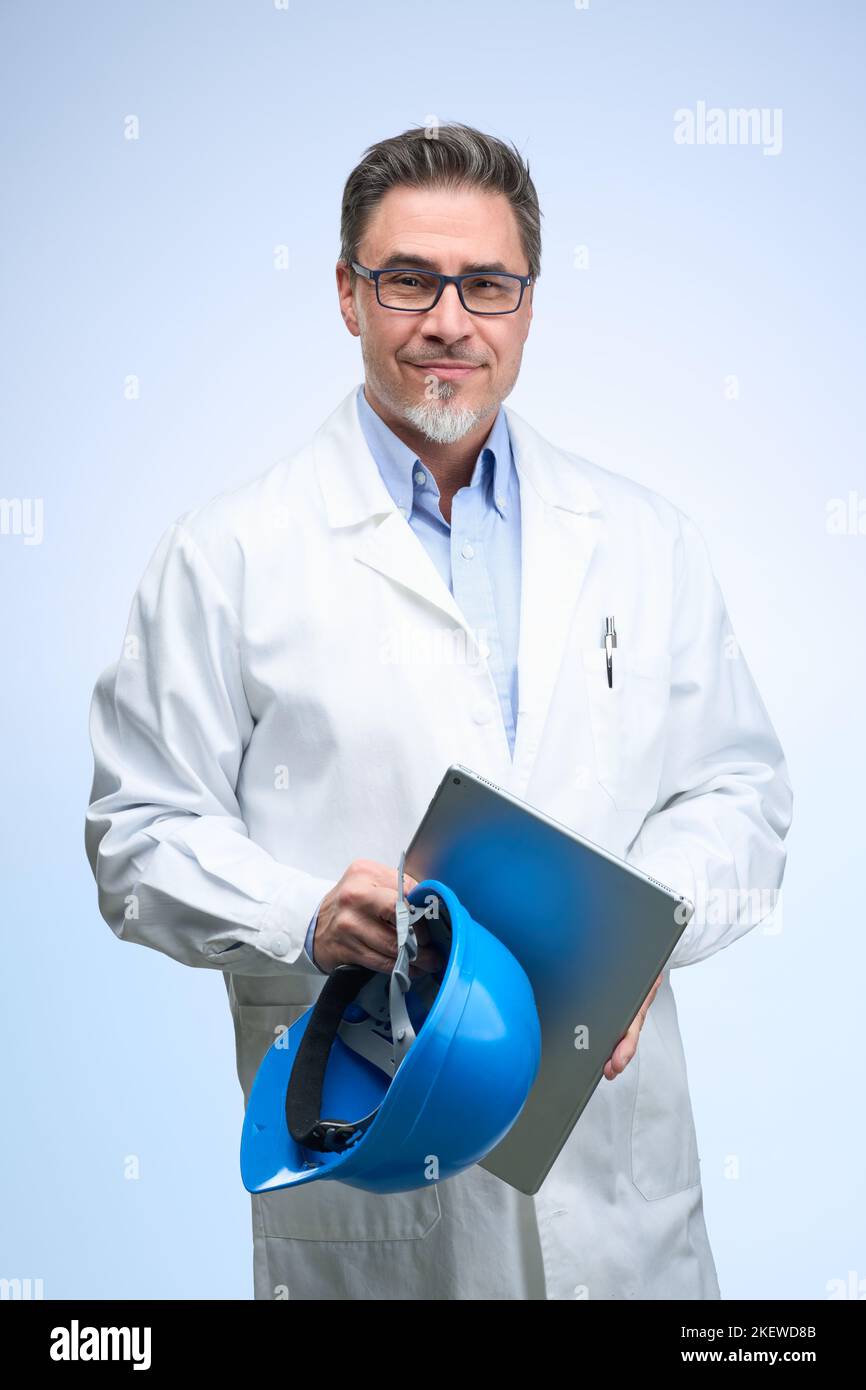 Middle age engineer in lab coat holding helmet. Scientist, architect with tablet. Mid adult ...