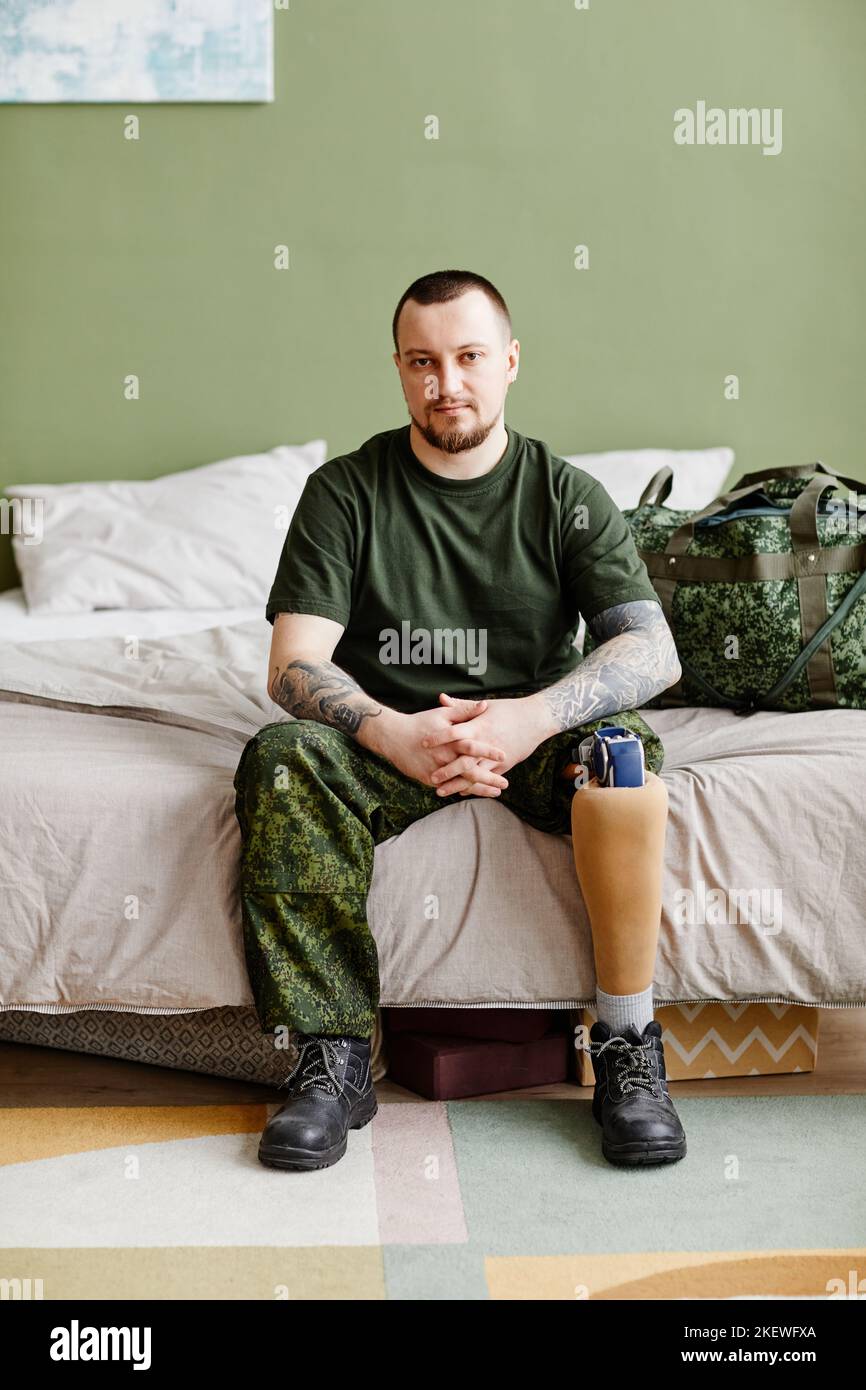 Full length portrait of military veteran with prosthetic leg looking at ...