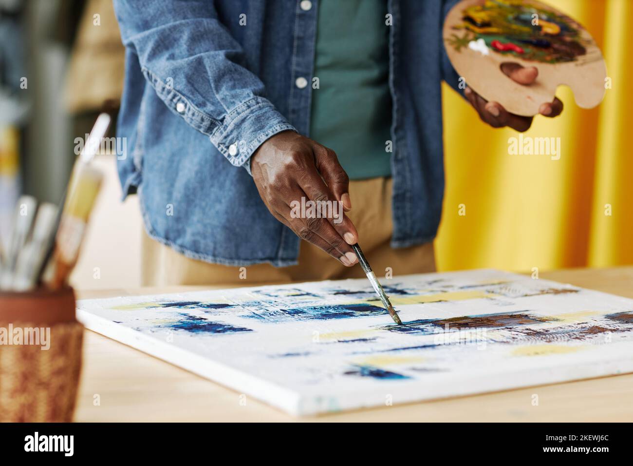 Hand of young African American male artist with color palette painting ...