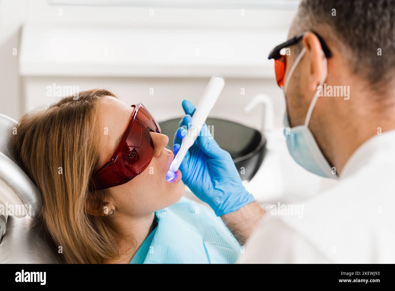 Uv illumination of photopolymer tooth filling procedure. Dentist in red ...