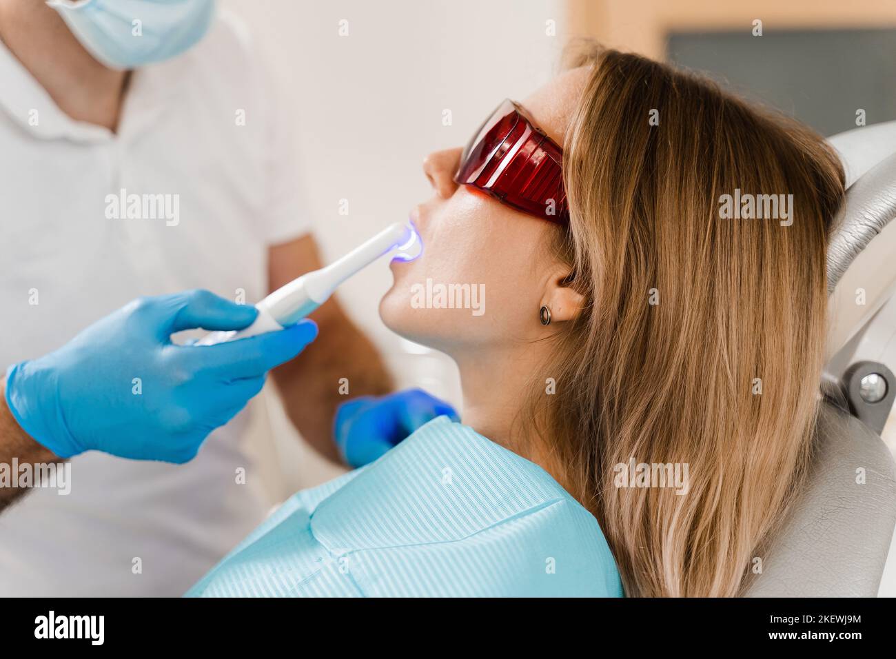 Dentist treats and removes caries in woman patient. Uv illumination of ...