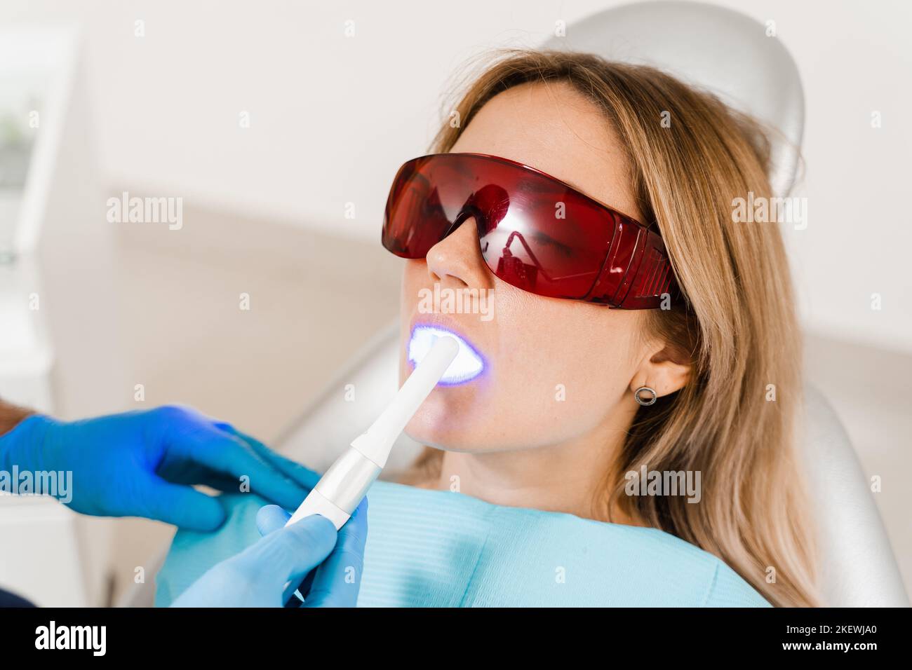 Dentist treats and removes caries in woman patient. Uv illumination of ...