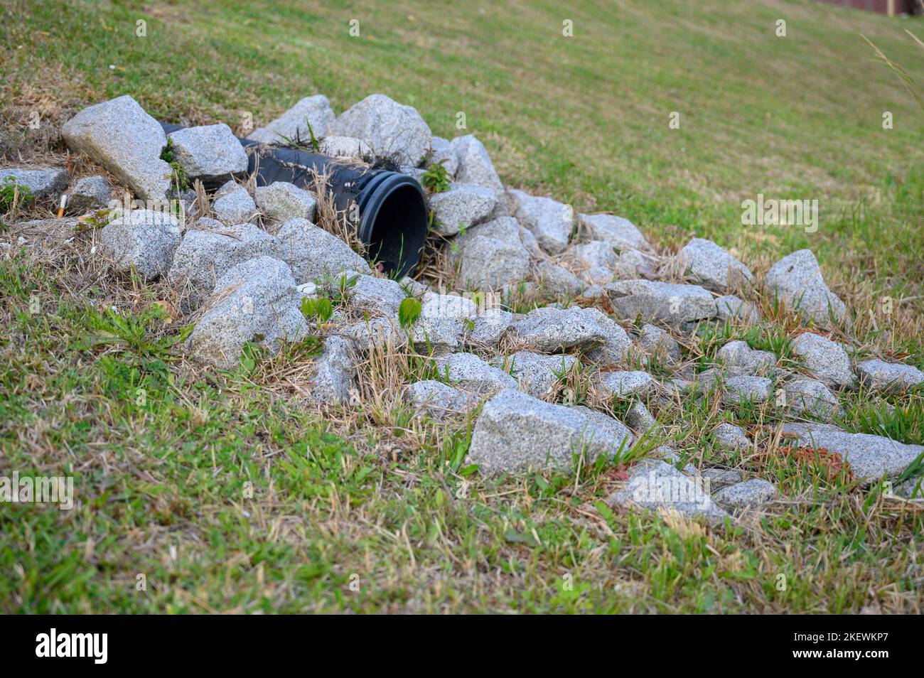 plastic storm water outlet with rip-rap protruding from a grass ...