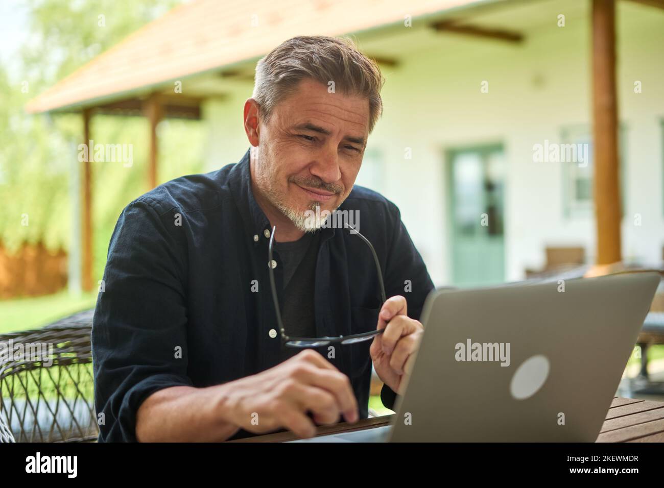 Middle aged man working with laptop computer at home outdoor in garden ...