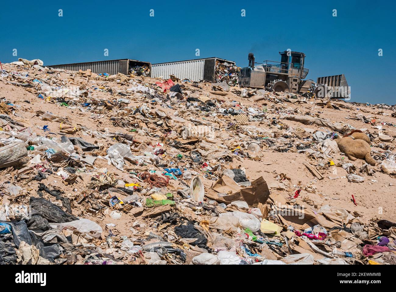 A soil compactor, and two trailers dumping trash at an active landfill ...