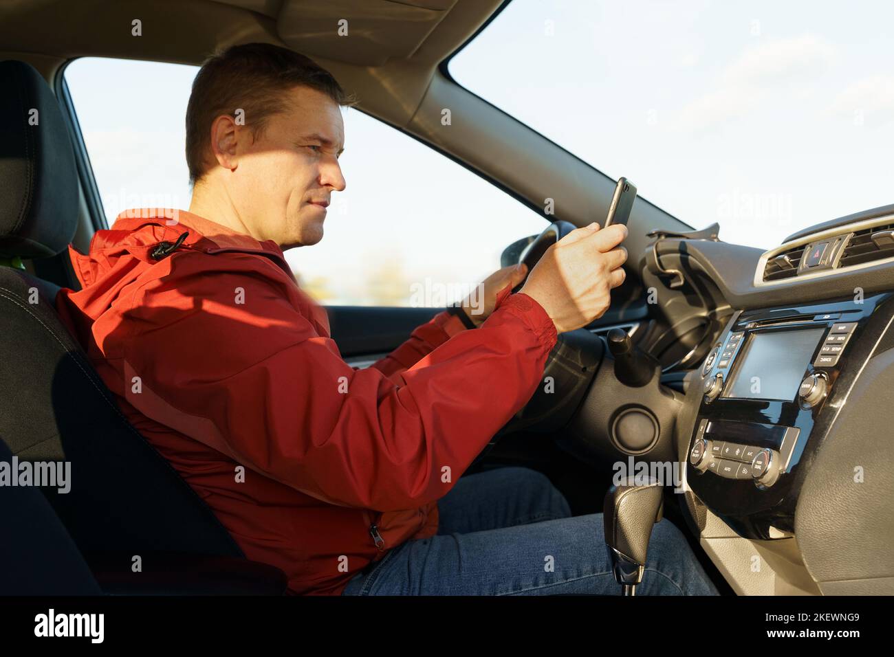 Driver man looks at the phone while the car is moving. Road safety ...
