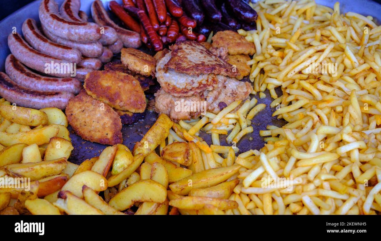 A large frying pan. Fried potatoes, sausages, meatballs, chops. Street ...