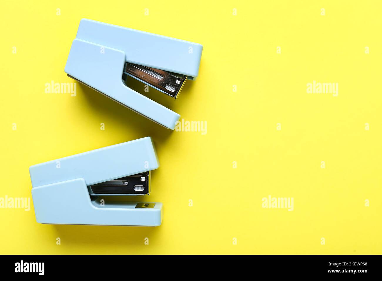 Office staplers on yellow background Stock Photo - Alamy