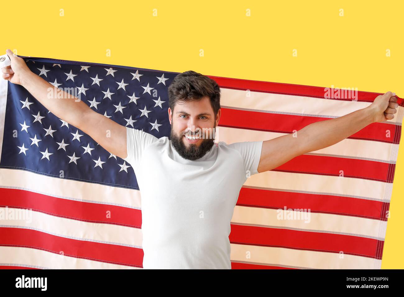 Handsome bearded man with USA flag on yellow background Stock Photo - Alamy