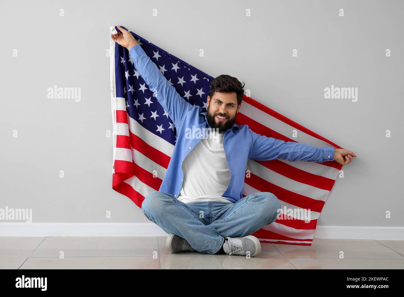 Handsome bearded man with USA flag sitting near grey wall Stock Photo ...