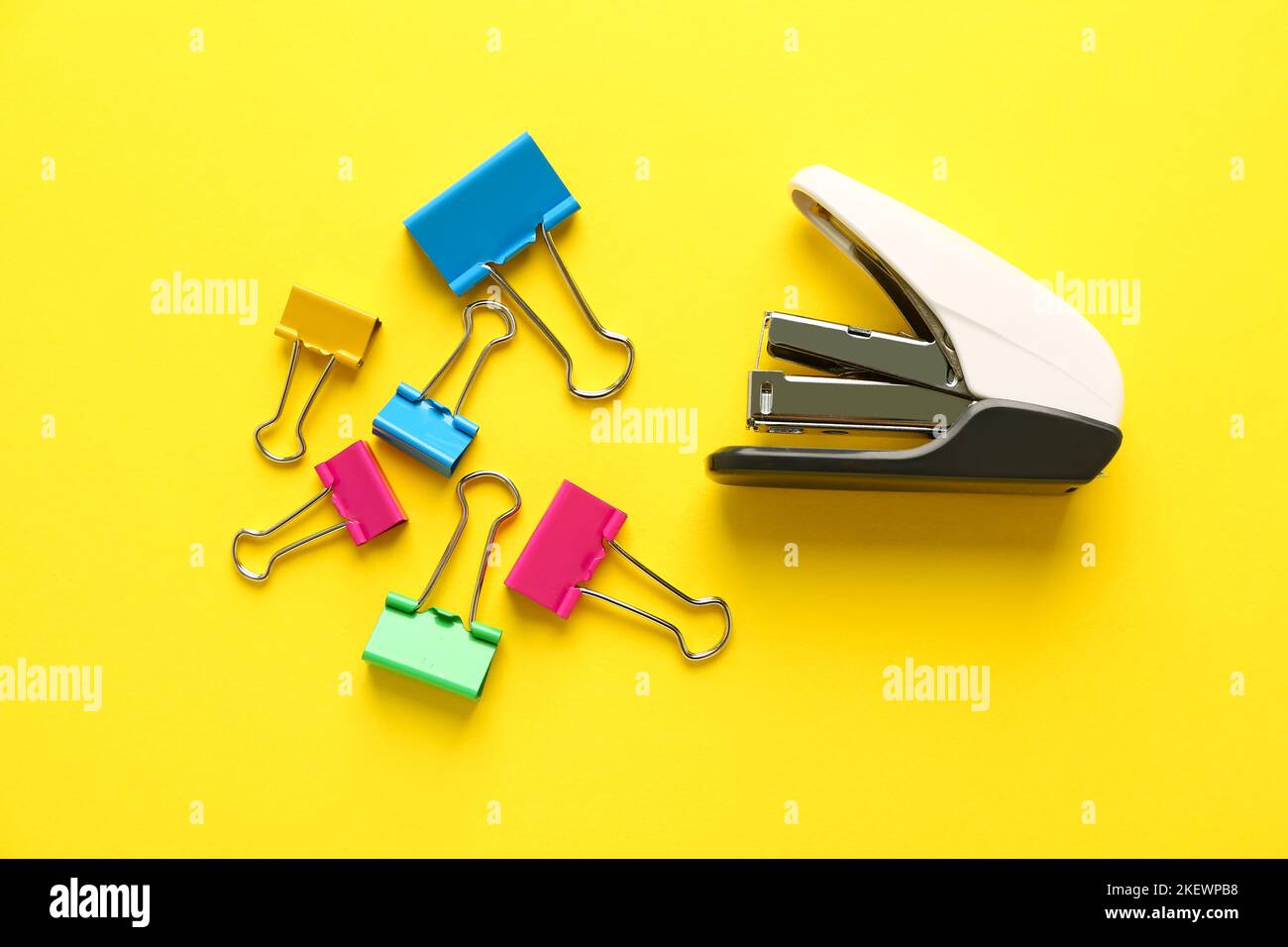 Office stapler and paper clips on yellow background Stock Photo - Alamy