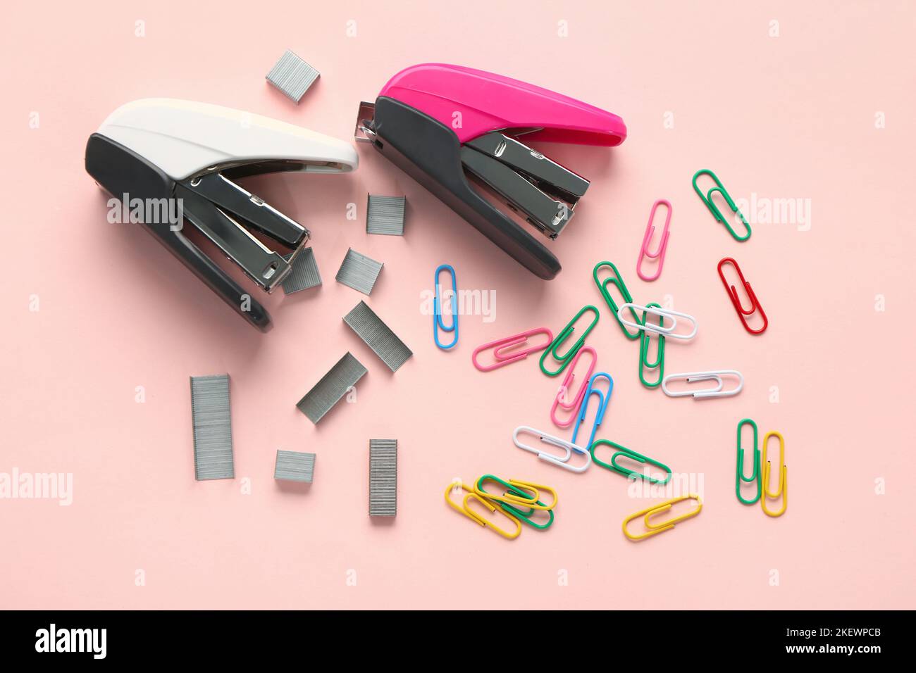 Office staplers, staples and paper clips on pink background Stock Photo ...