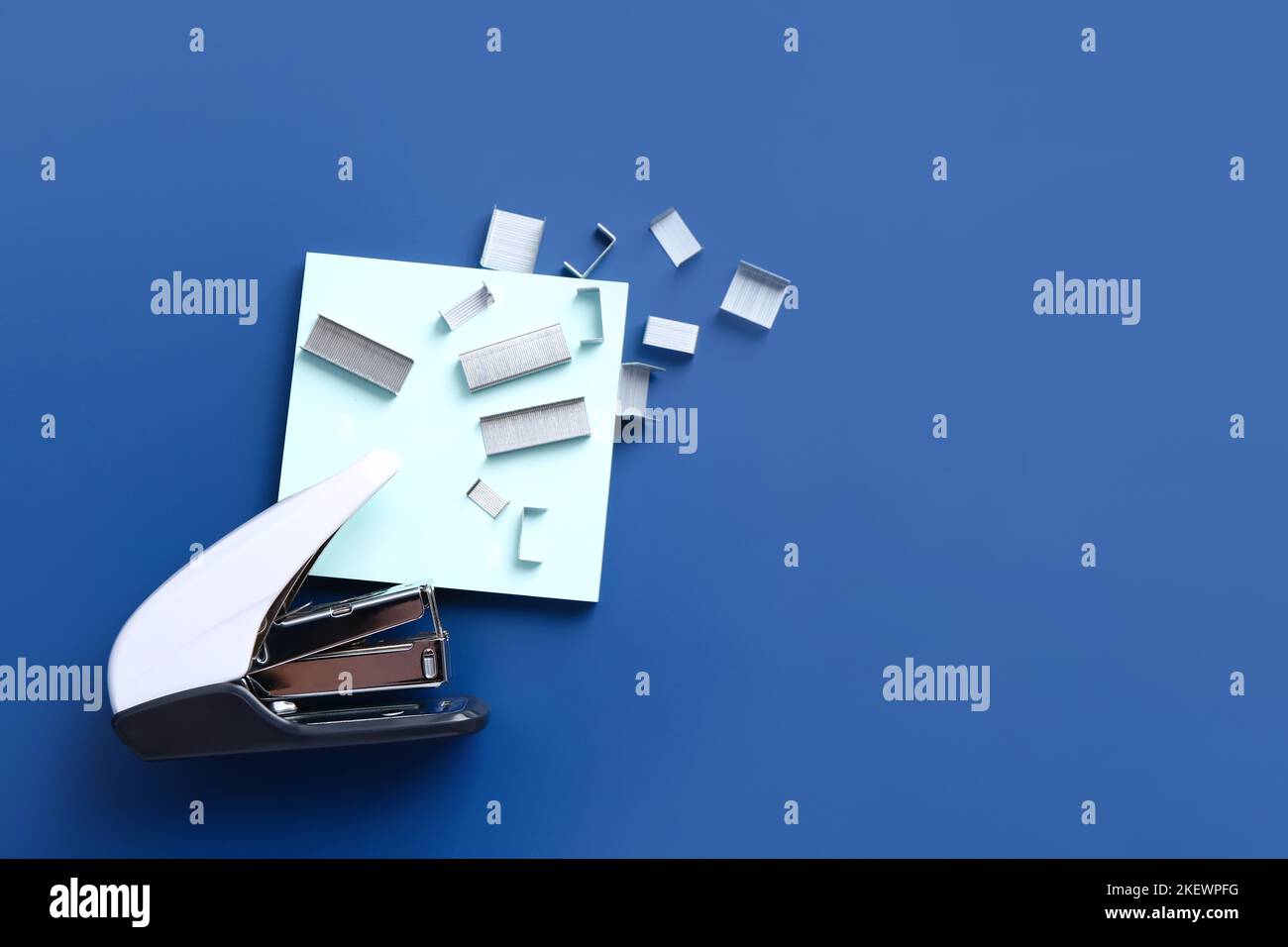 Stapler, staples and sticky notes on blue background Stock Photo - Alamy