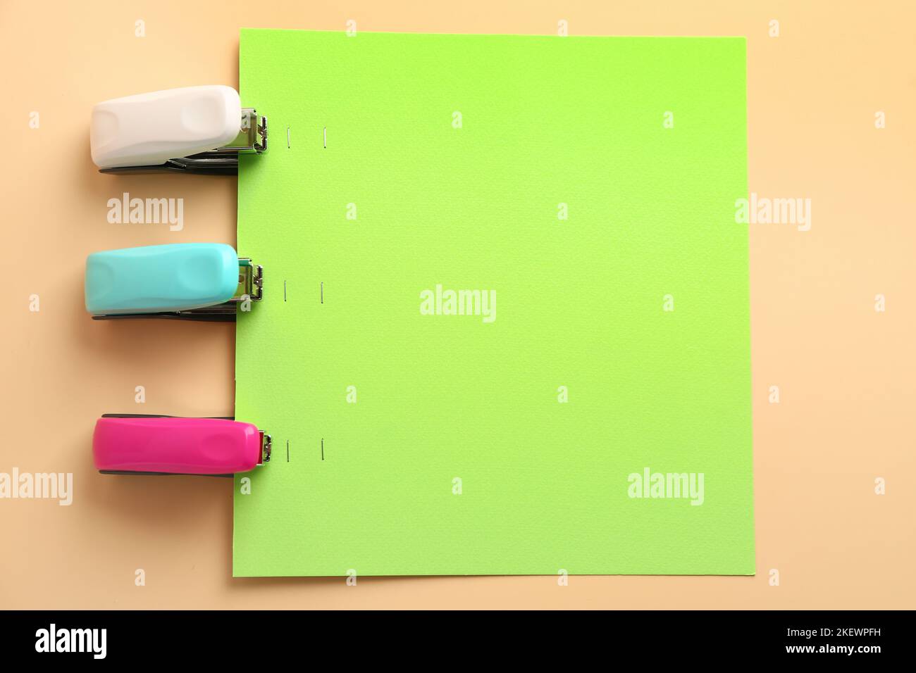 Different staplers with green sheet of paper on color background Stock ...