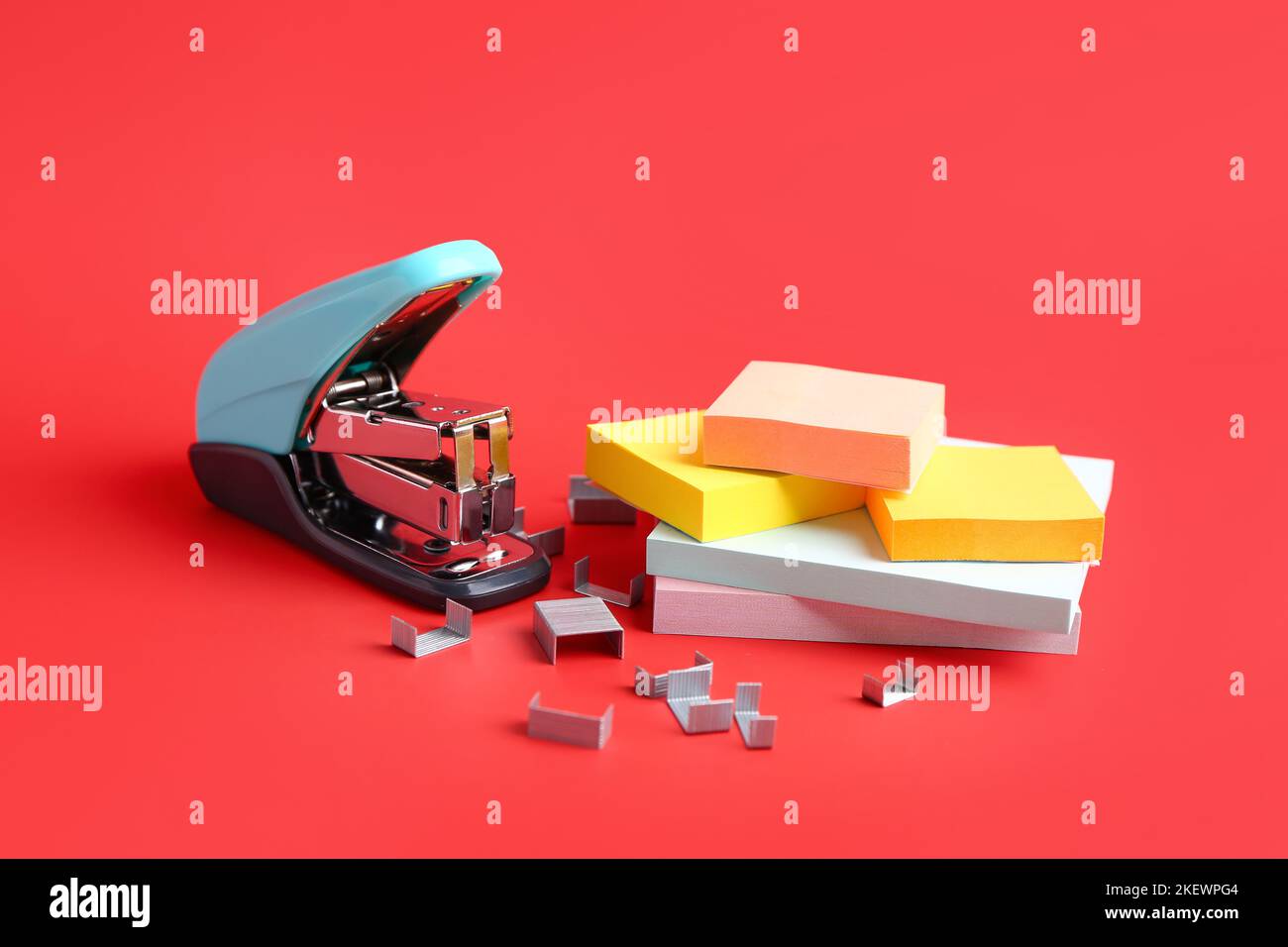 Stapler, staples and sticky notes on red background Stock Photo - Alamy