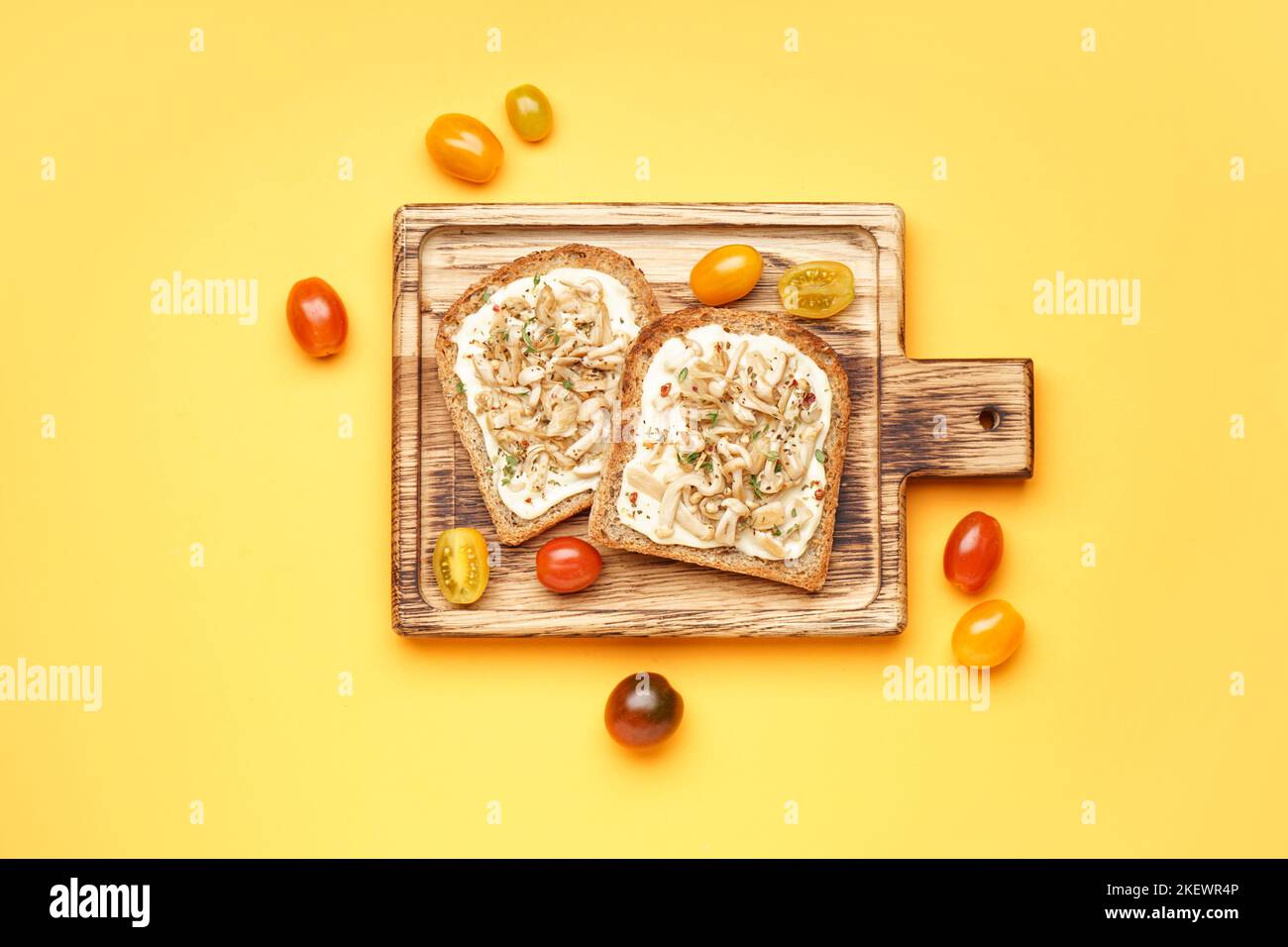 Wooden board of tasty toasts with cream cheese, mushrooms and tomatoes ...