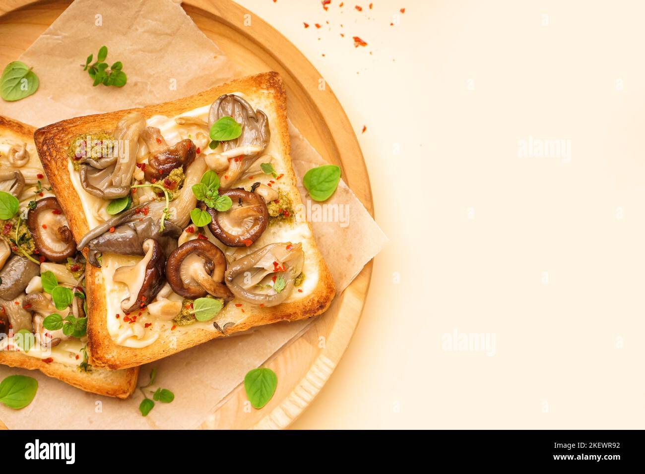Wooden plate of delicious toasts with cream cheese, mushrooms and pesto ...