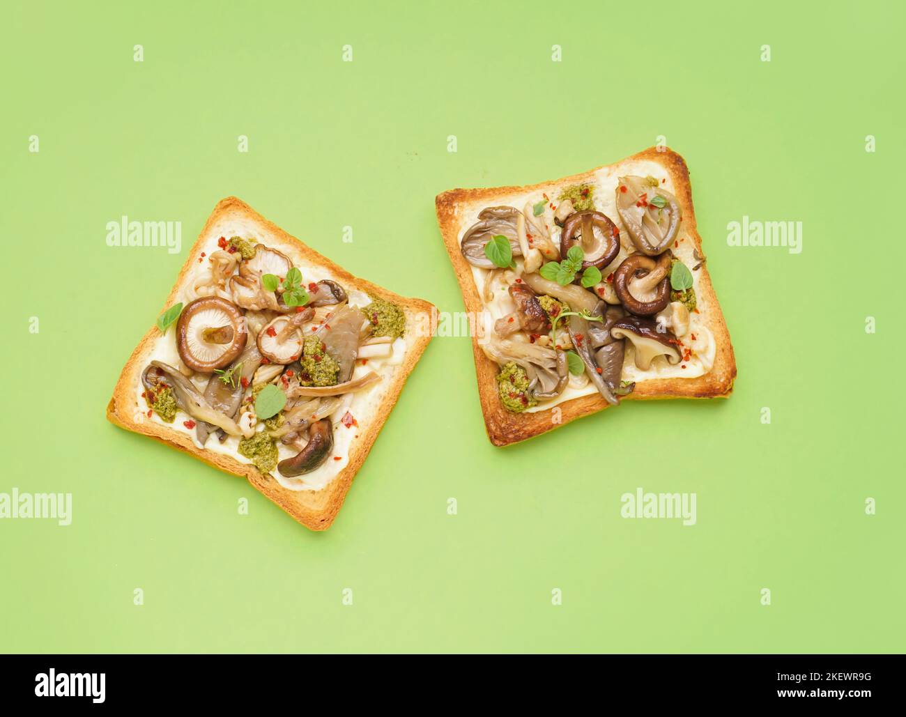 Delicious toasts with cream cheese, mushrooms and pesto sauce on green ...