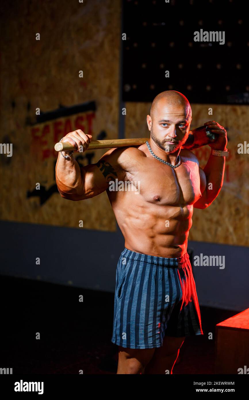 Strong athletic man posing with a sports hammer on the background of ...