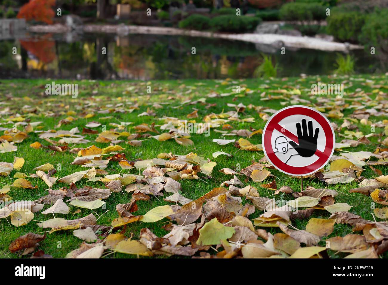 No access for unauthorised persons sign with fallen leaves on green ...