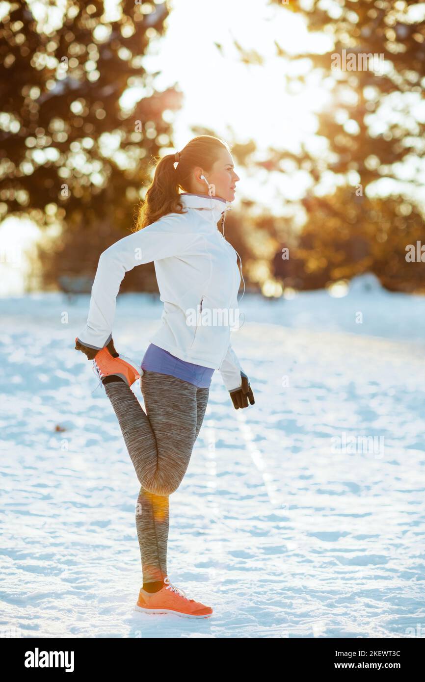 Full length portrait of fitness woman in white jacket stretching ...