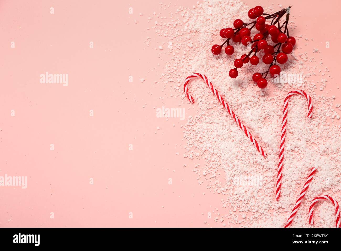 Composition with red berries, candy canes and snow on pink background ...