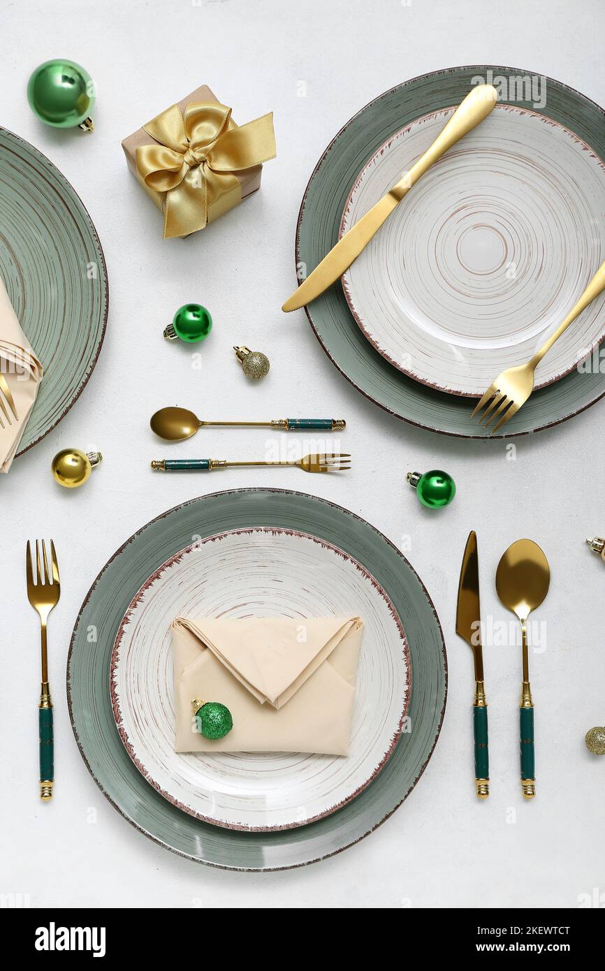 Beautiful table setting with Christmas balls and gift on white ...