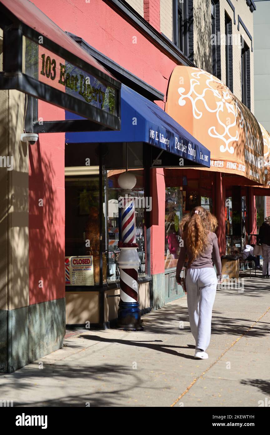 Ann Arbor, Michigan, USA. Woman walking along a street lined with shops ...