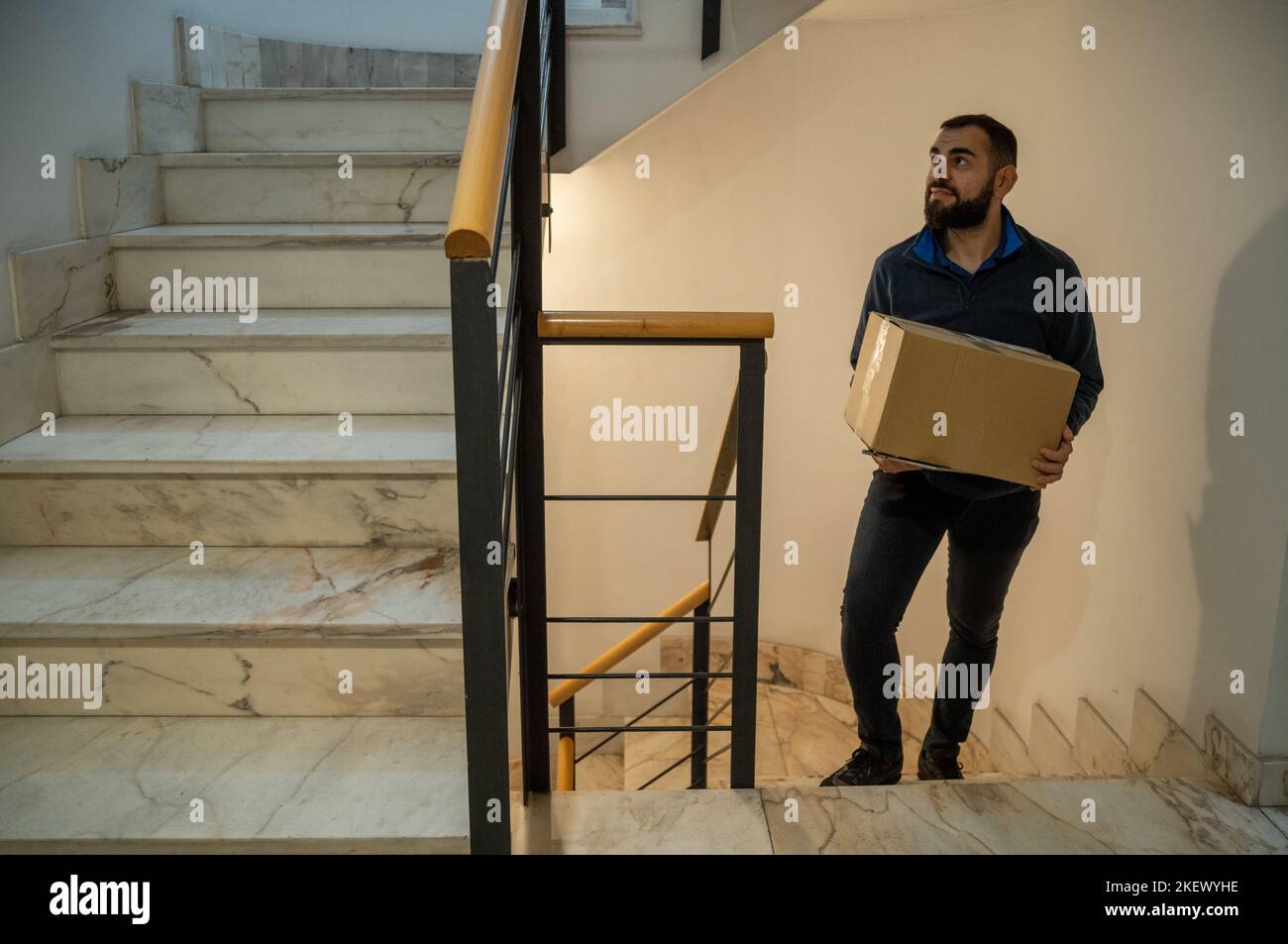 Delivery man going up the steps carrying a parcel on his hands Stock ...