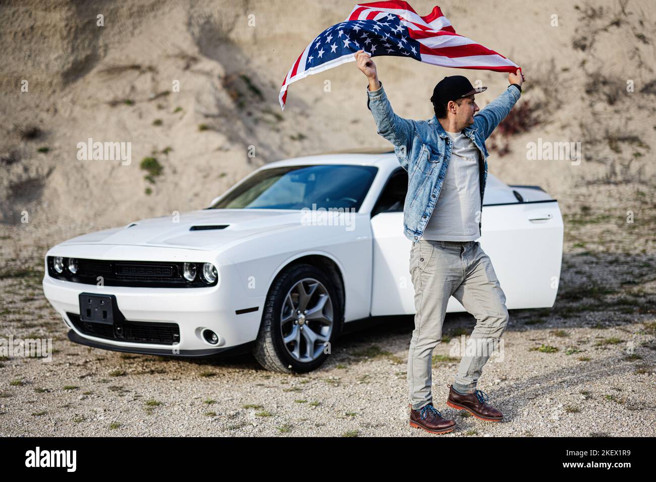 Handsome man in jeans jacket and cap with USA flag near his white ...