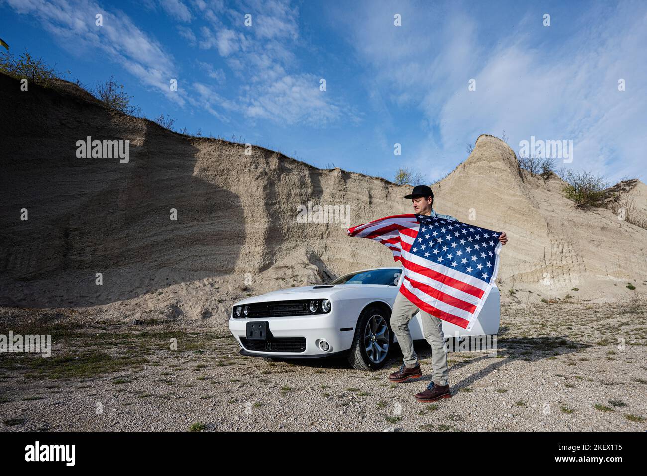 Handsome man in jeans jacket and cap with USA flag near his white ...